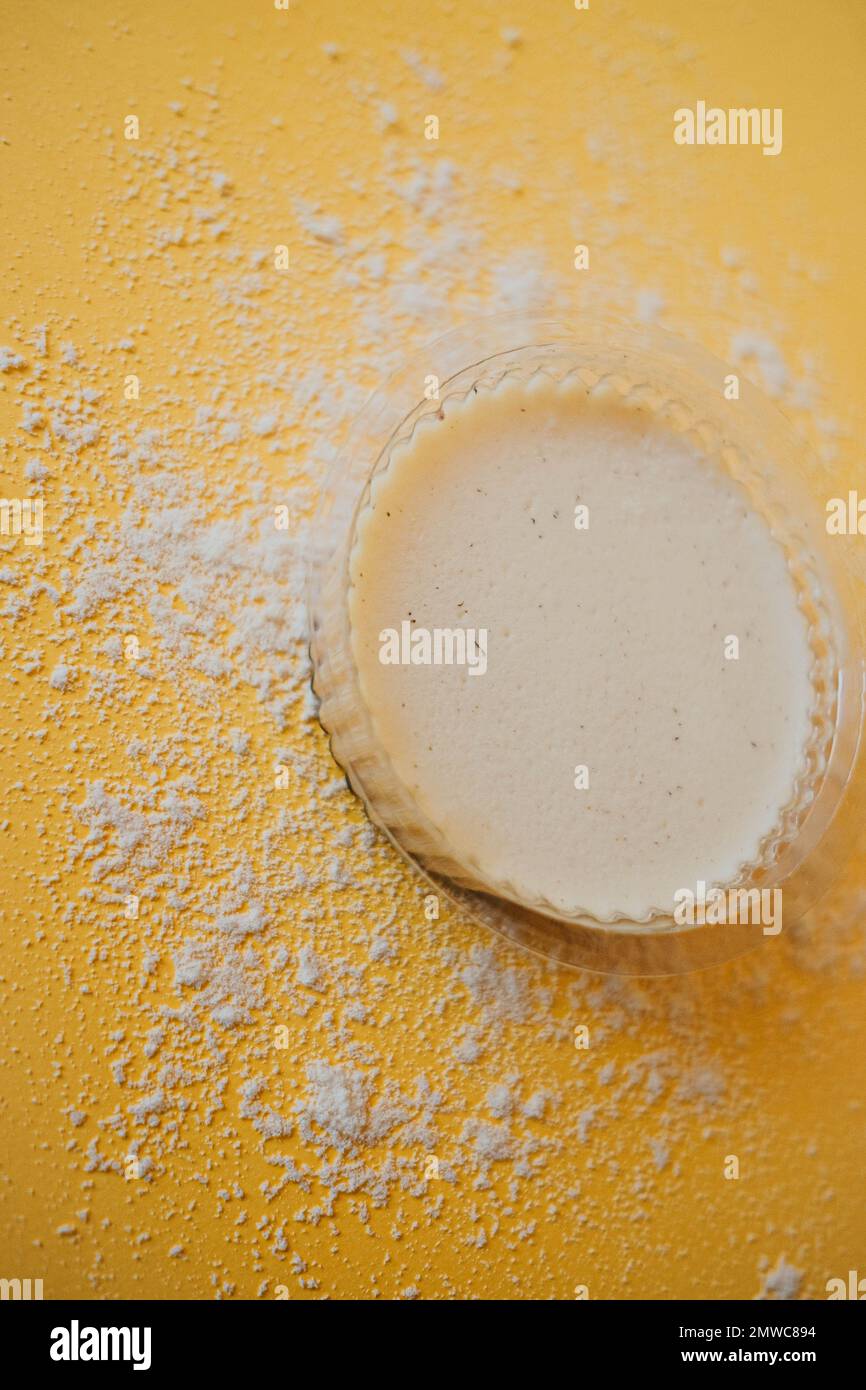 A vertical shot of a plastic bowl of creamy pudding on a yellow ...