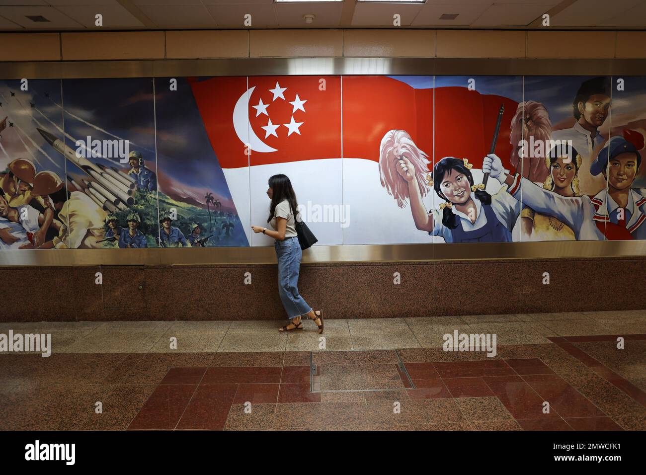 A Commuter walks past a mural in the Raffles Place MRT Station in ...