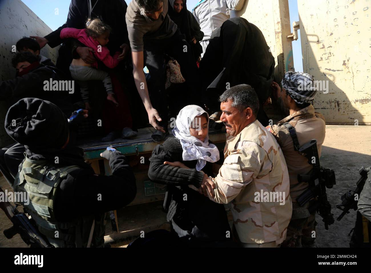 Iraqi Army soldiers help displaced civilians as they fleeing their ...