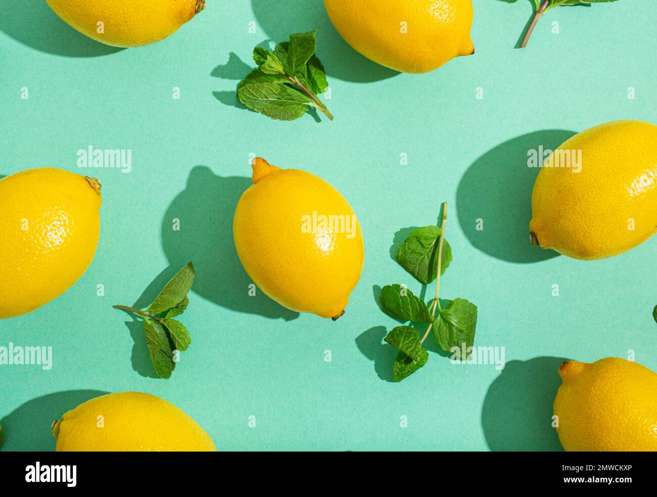 Fresh yellow lemons with mint on minimal blue background on bright sun ...