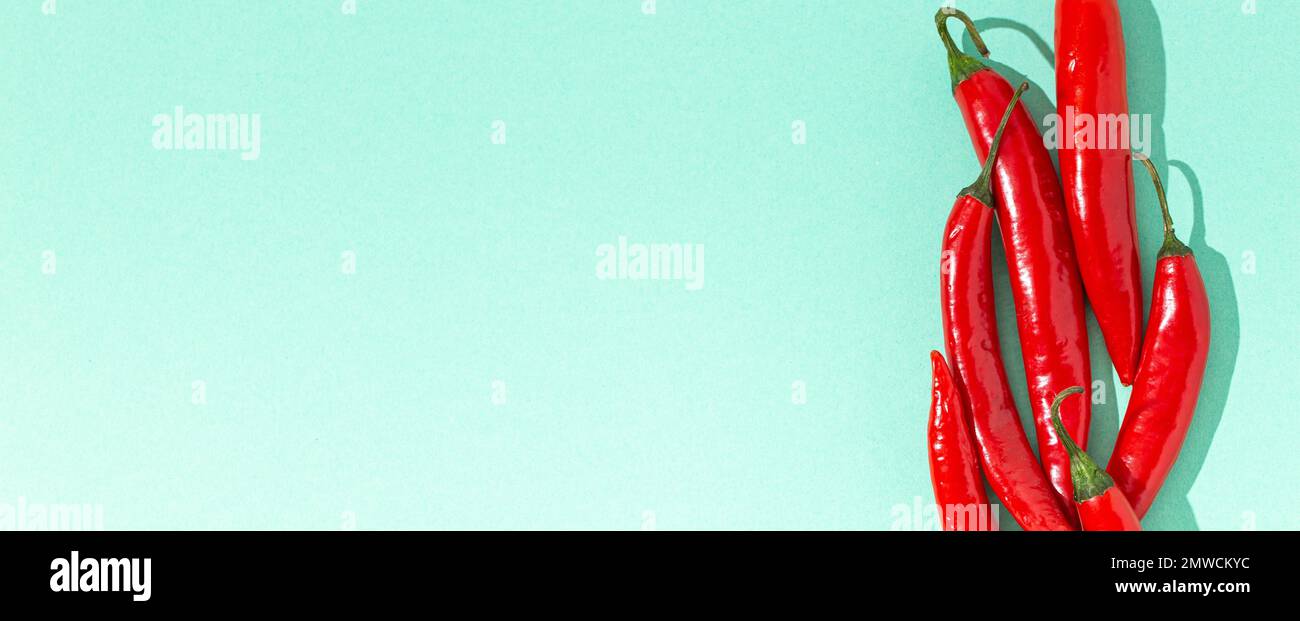 Red hot chilli peppers on minimal blue contrast background close up ...