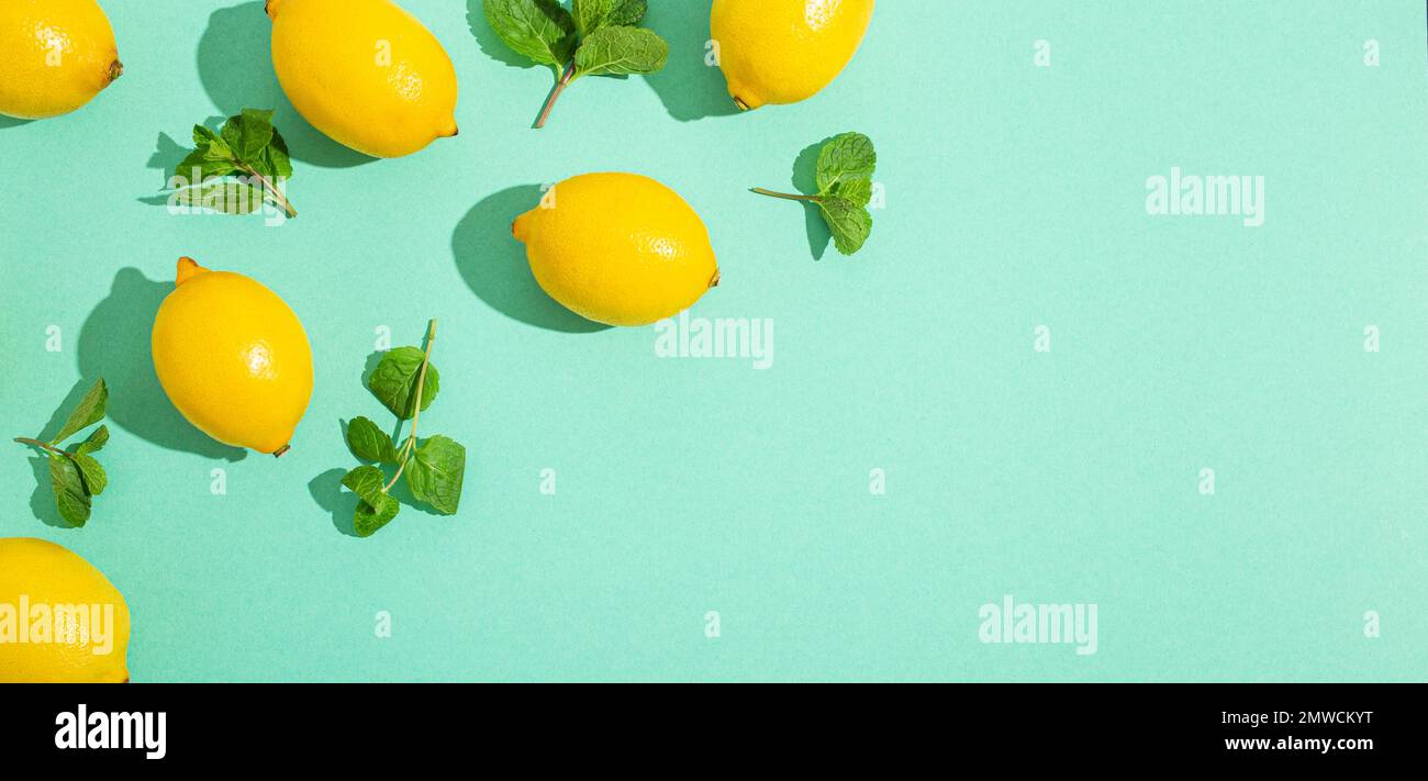 Fresh yellow lemons with mint on minimal blue background on bright sun ...