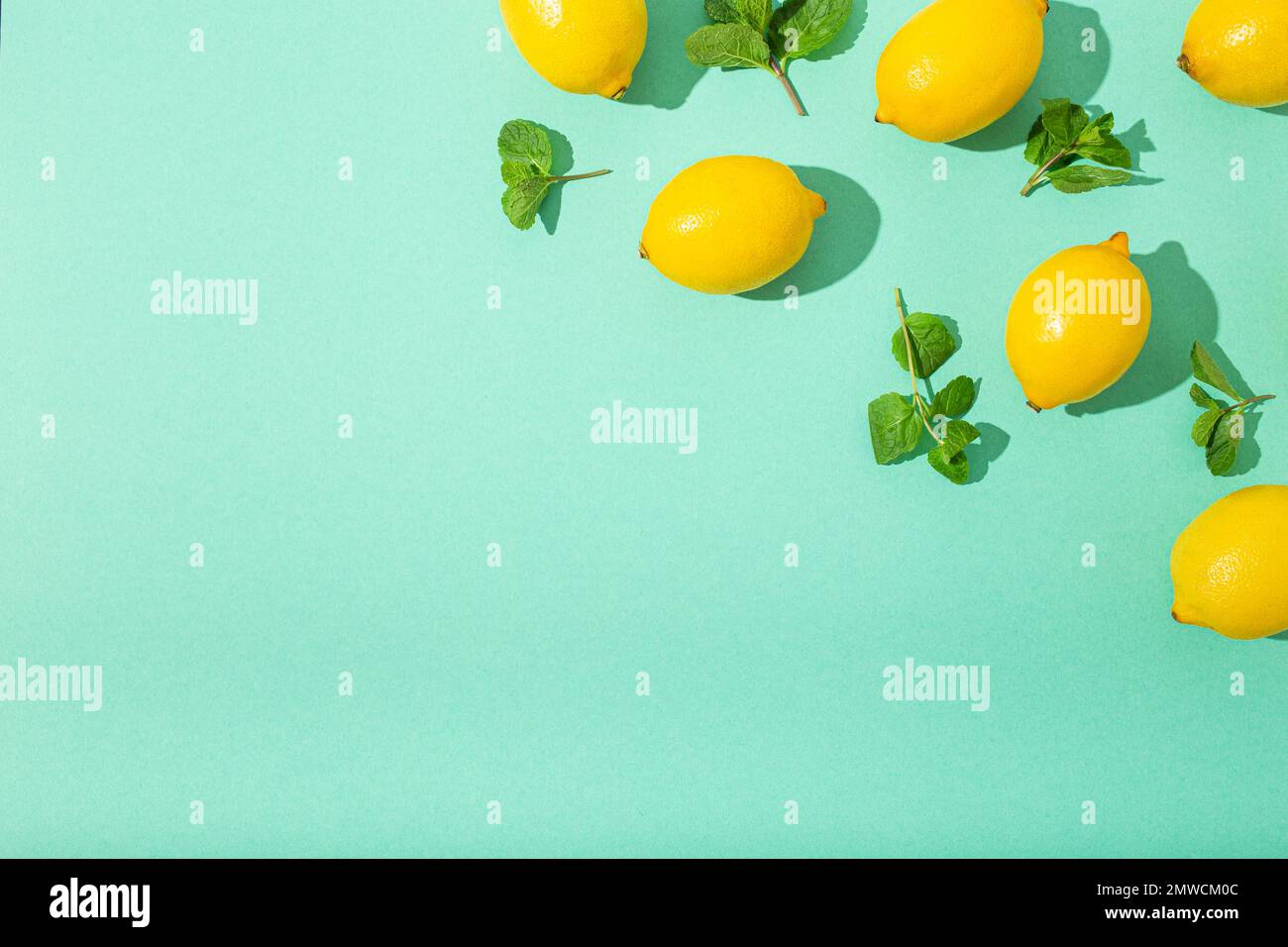 Fresh yellow lemons with mint on minimal blue background on bright sun ...