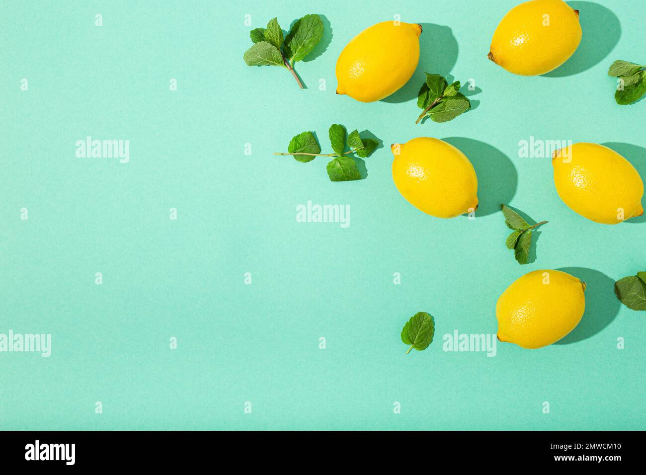 Fresh yellow lemons with mint on minimal blue background on bright sun ...