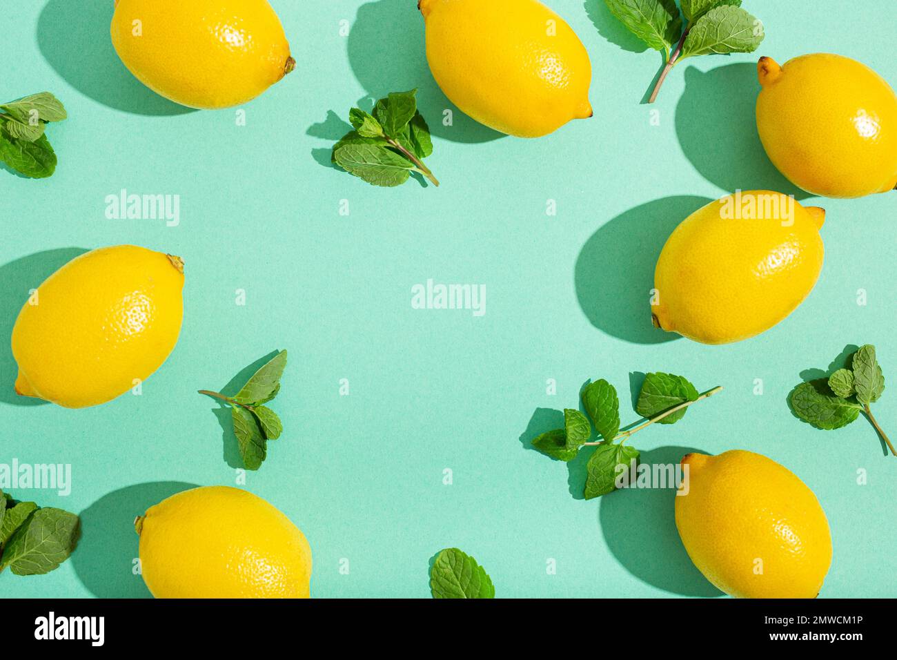 Fresh yellow lemons with mint on minimal blue background on bright sun ...