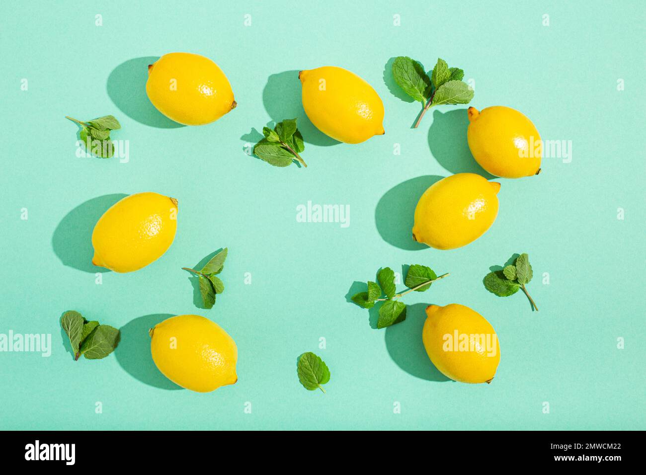 Fresh yellow lemons with mint on minimal blue background on bright sun ...