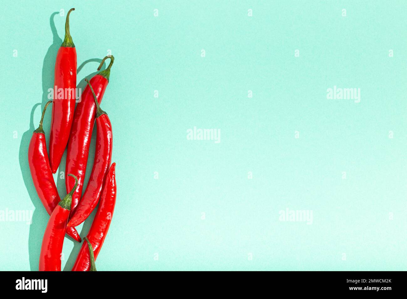 Red hot chilli peppers on minimal blue contrast background close up ...