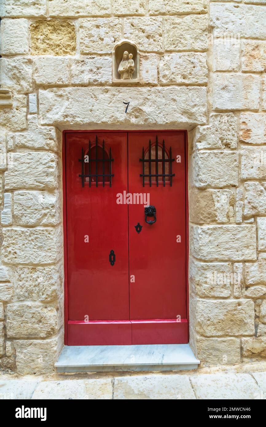 Old red painted with black wrought iron bars wooden entrance door with ...