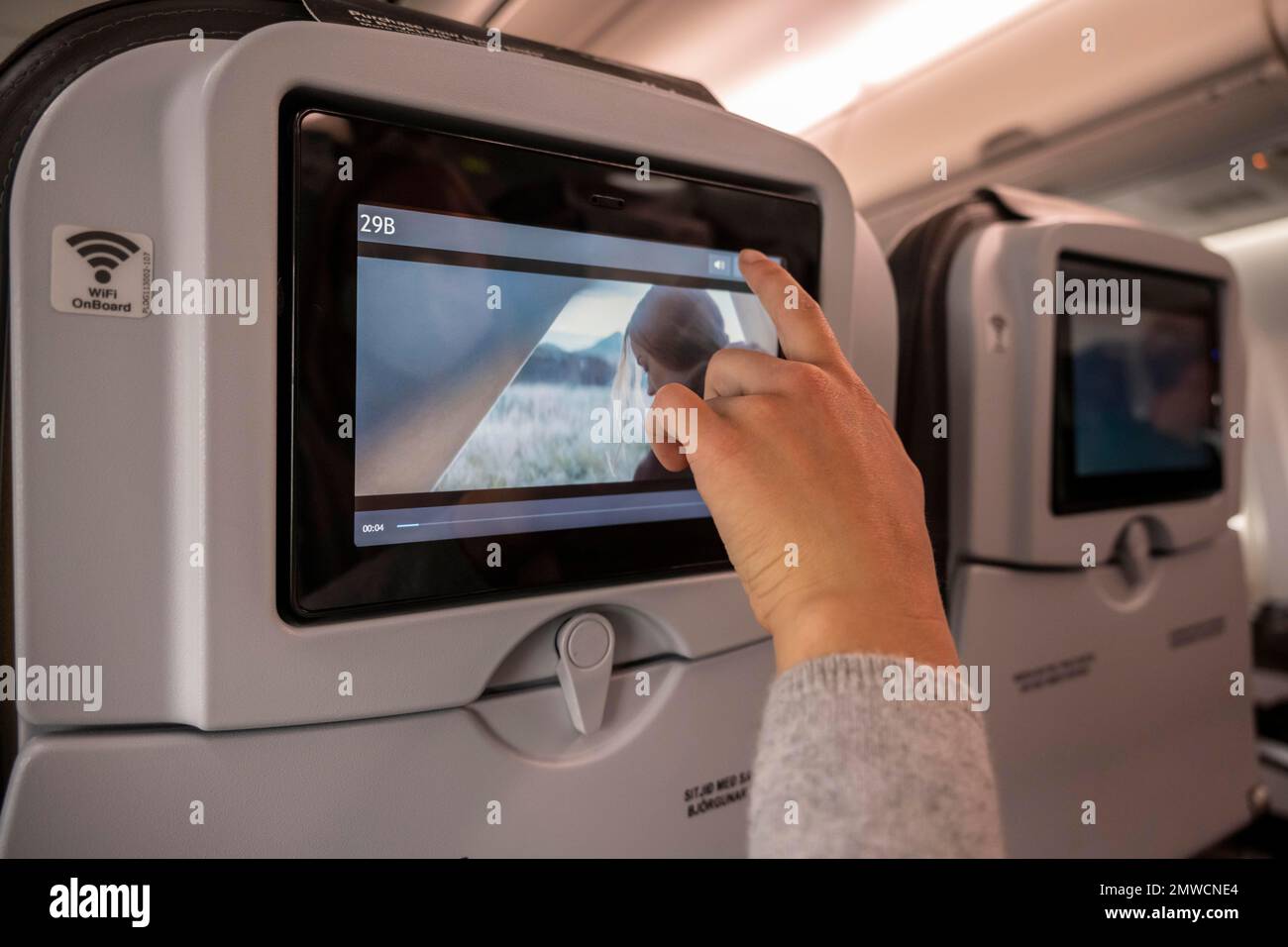Hand operates computer screen, entertainment, rows of seats in an ...
