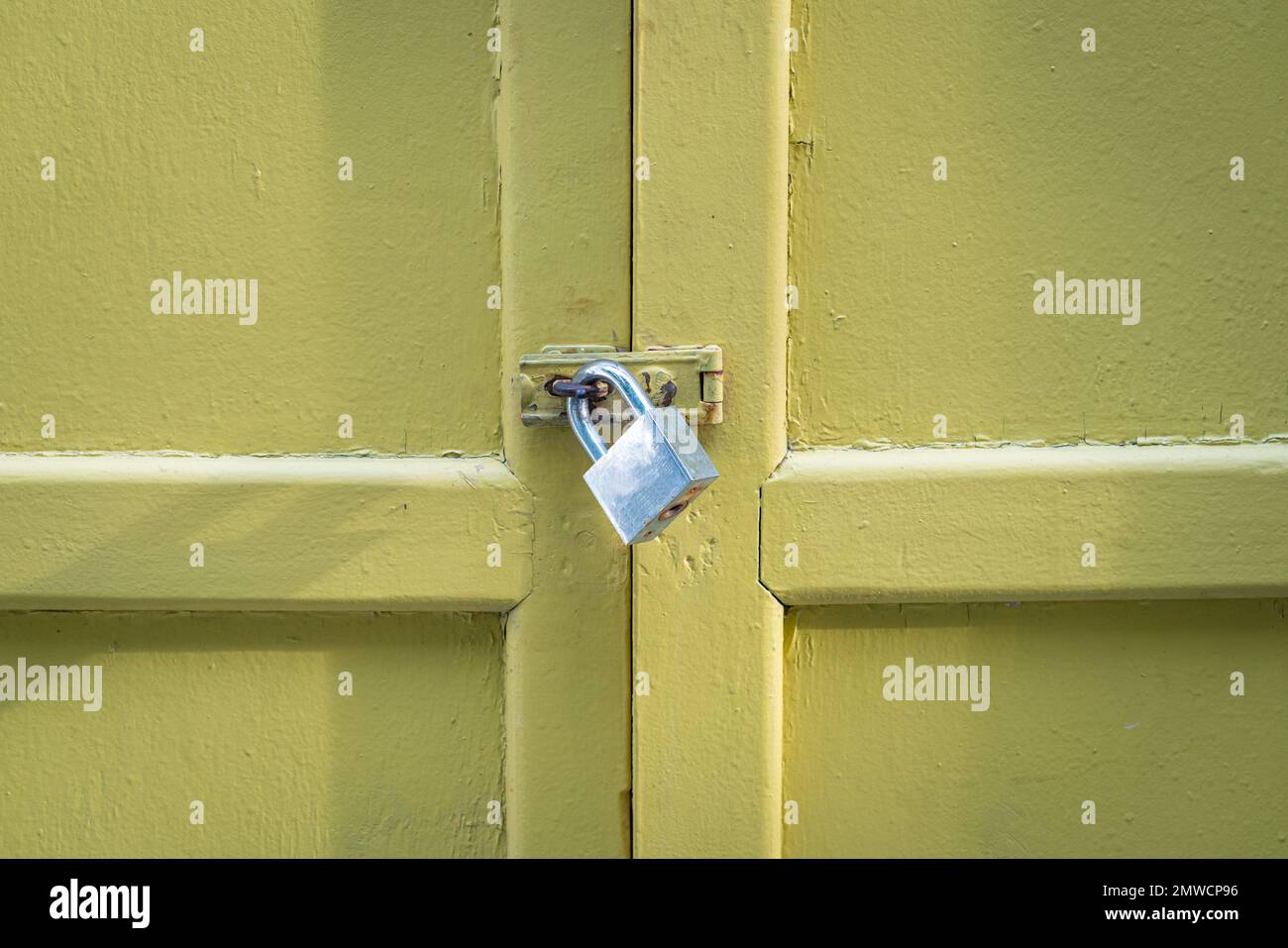 Rustic yellow wood door closed with padlock. Security concept, copy ...