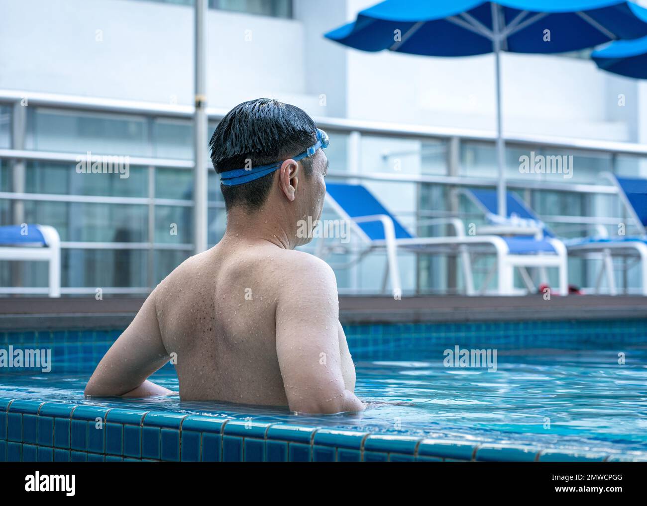 Back view of man in the pool, relaxing by the side. Vacation or travel ...