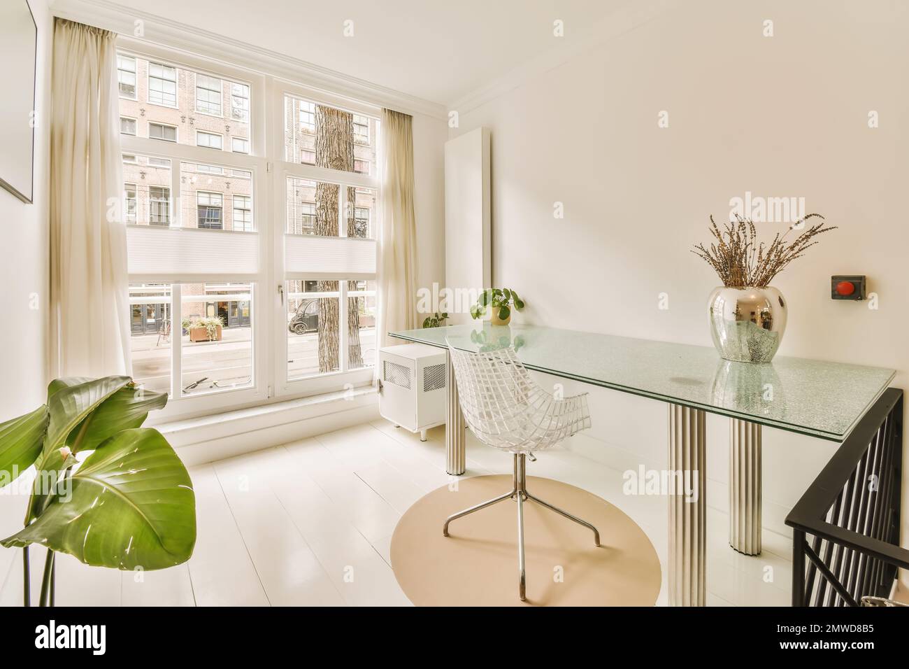 a room with a desk, chair and large window looking out onto the street ...