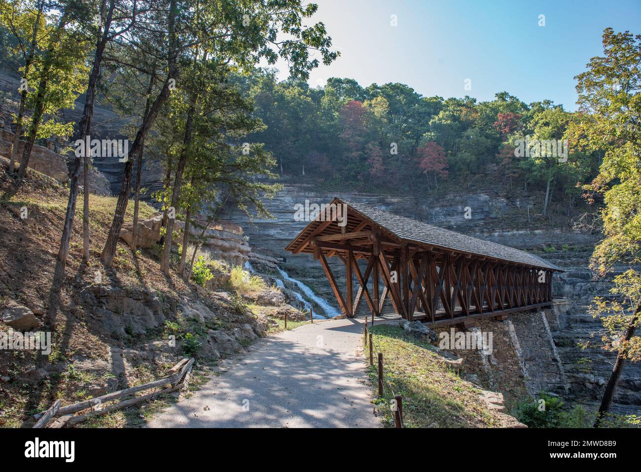 A timber frame-covered bridge surrounded by rocks, trees and a ...