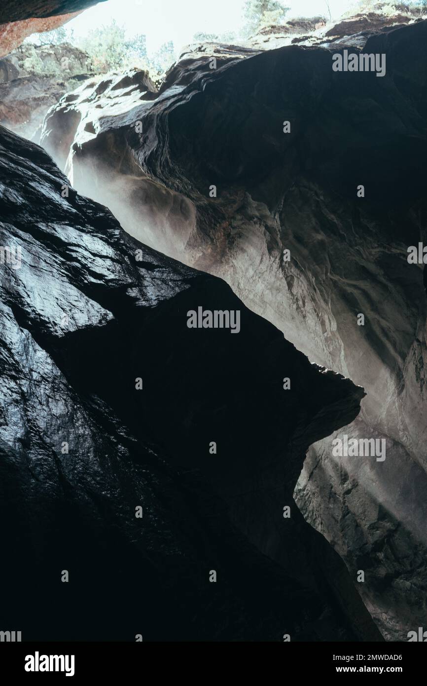 A vertical shot of a view from inside a rugged cave looking out through ...