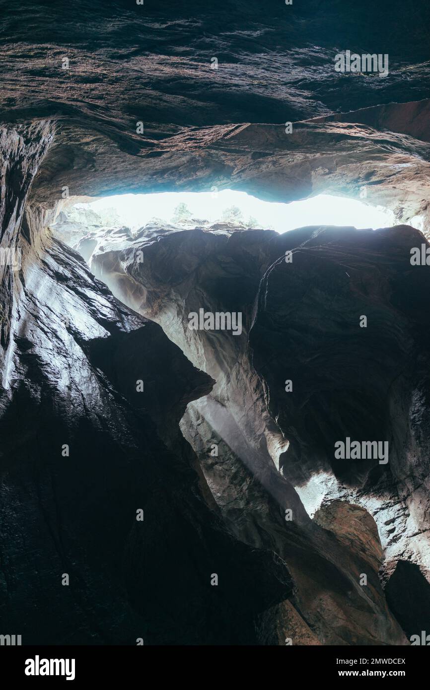 A vertical shot of a view from inside a rugged cave looking out through ...