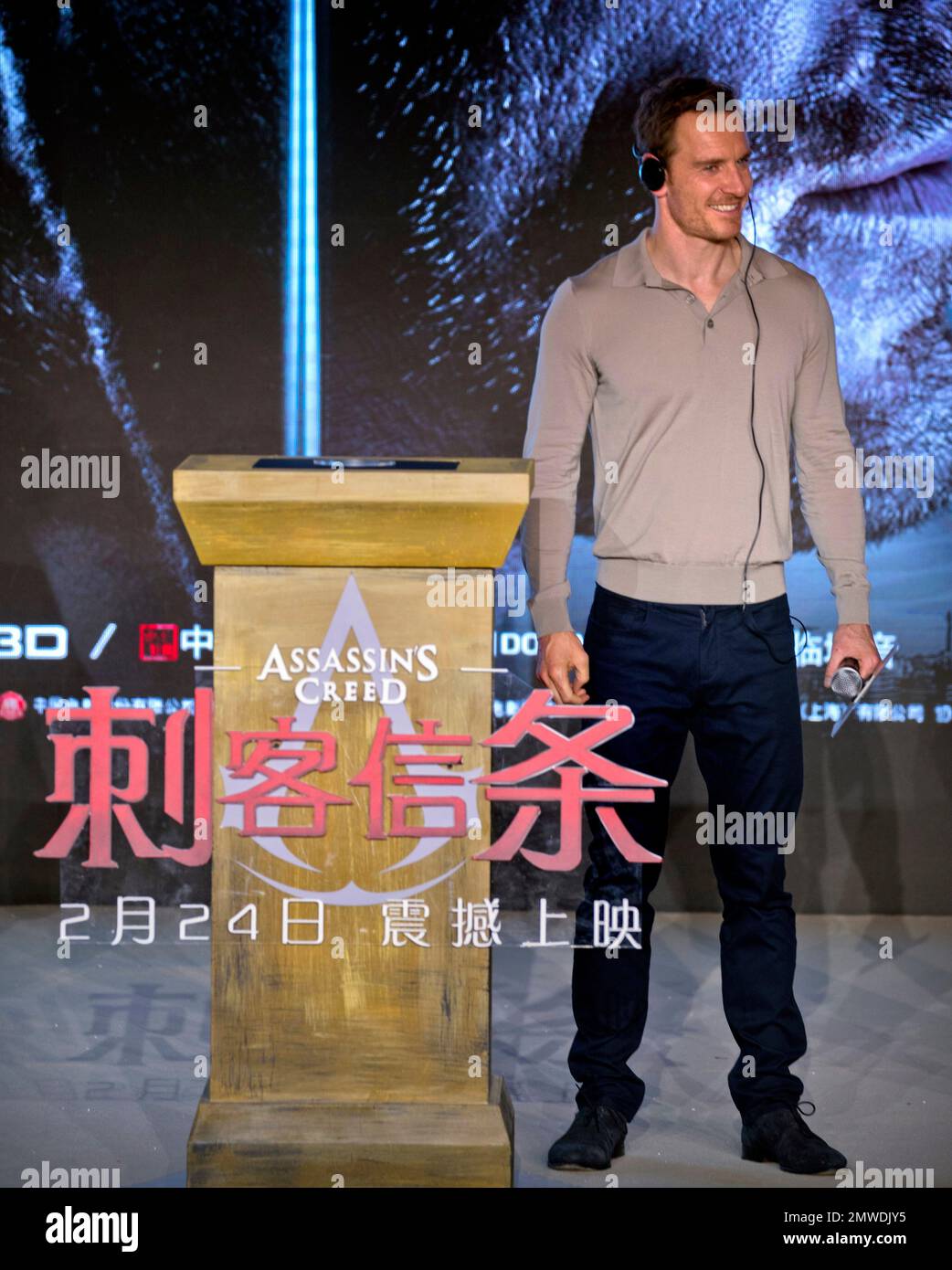 Actor Michael Fassbender stands next to a podium with the logo of his ...