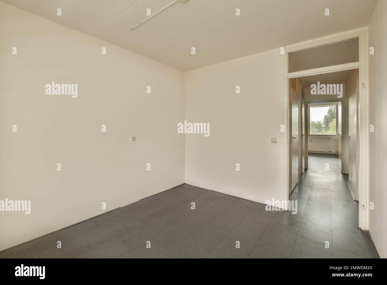 an empty room with white walls and black tiles on the floor there is a ...
