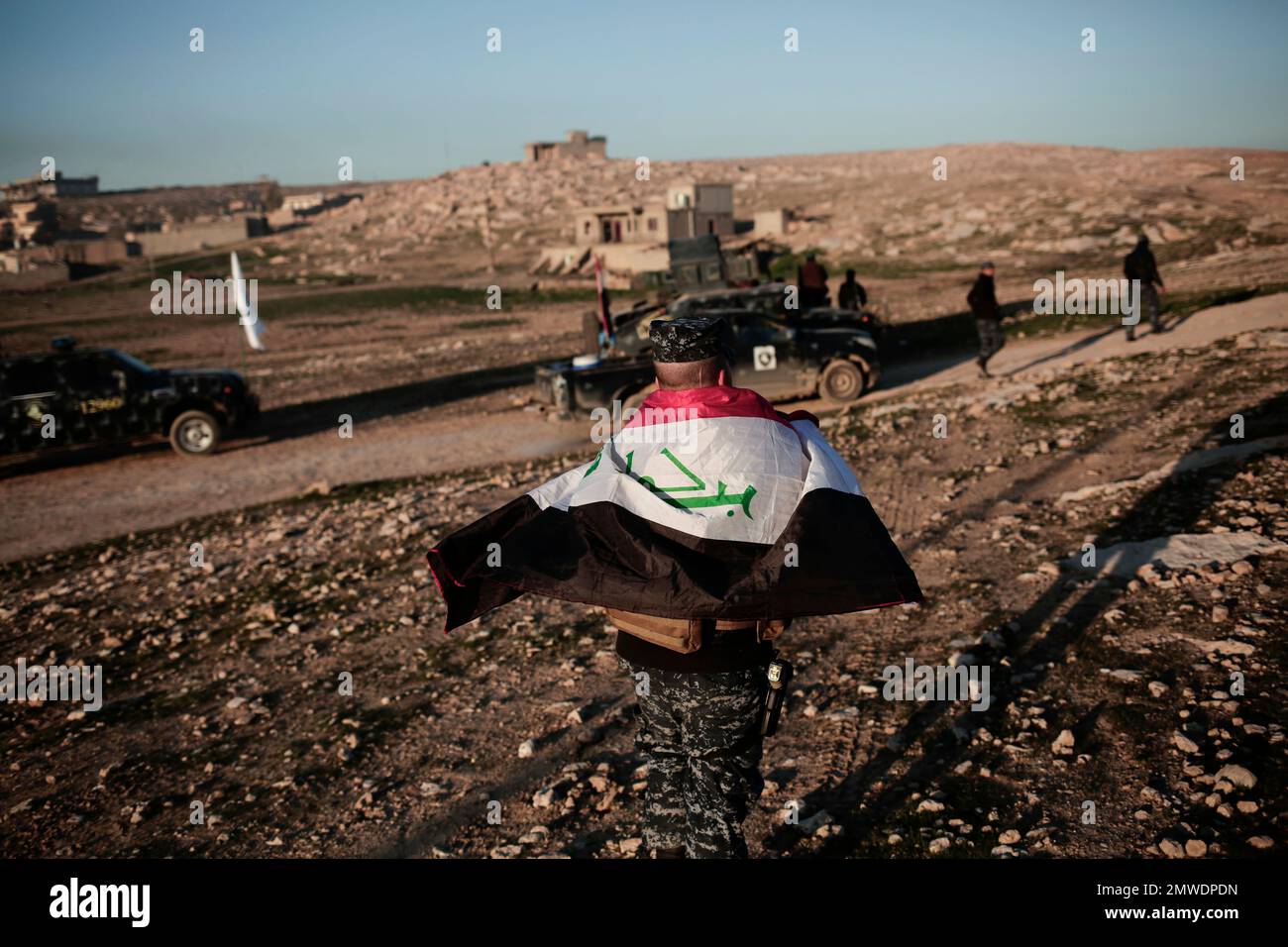 A member of the Iraqi federal police wears an Iraqi flag around his ...