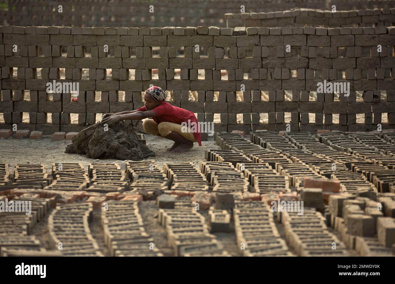 An Indian girl makes bricks at a brick kiln on the outskirts of Gauhati ...