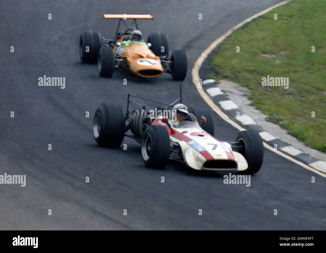John Surtees, number 7, is followed by Bruce McLaren, number 2, at the ...