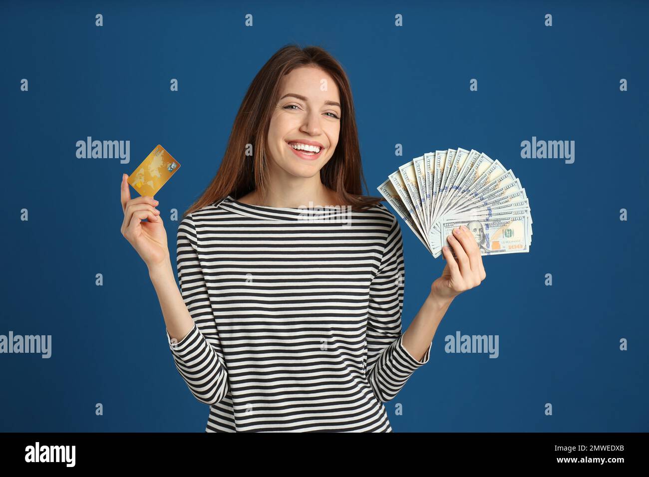 Happy young woman with cash money and credit card on blue background ...