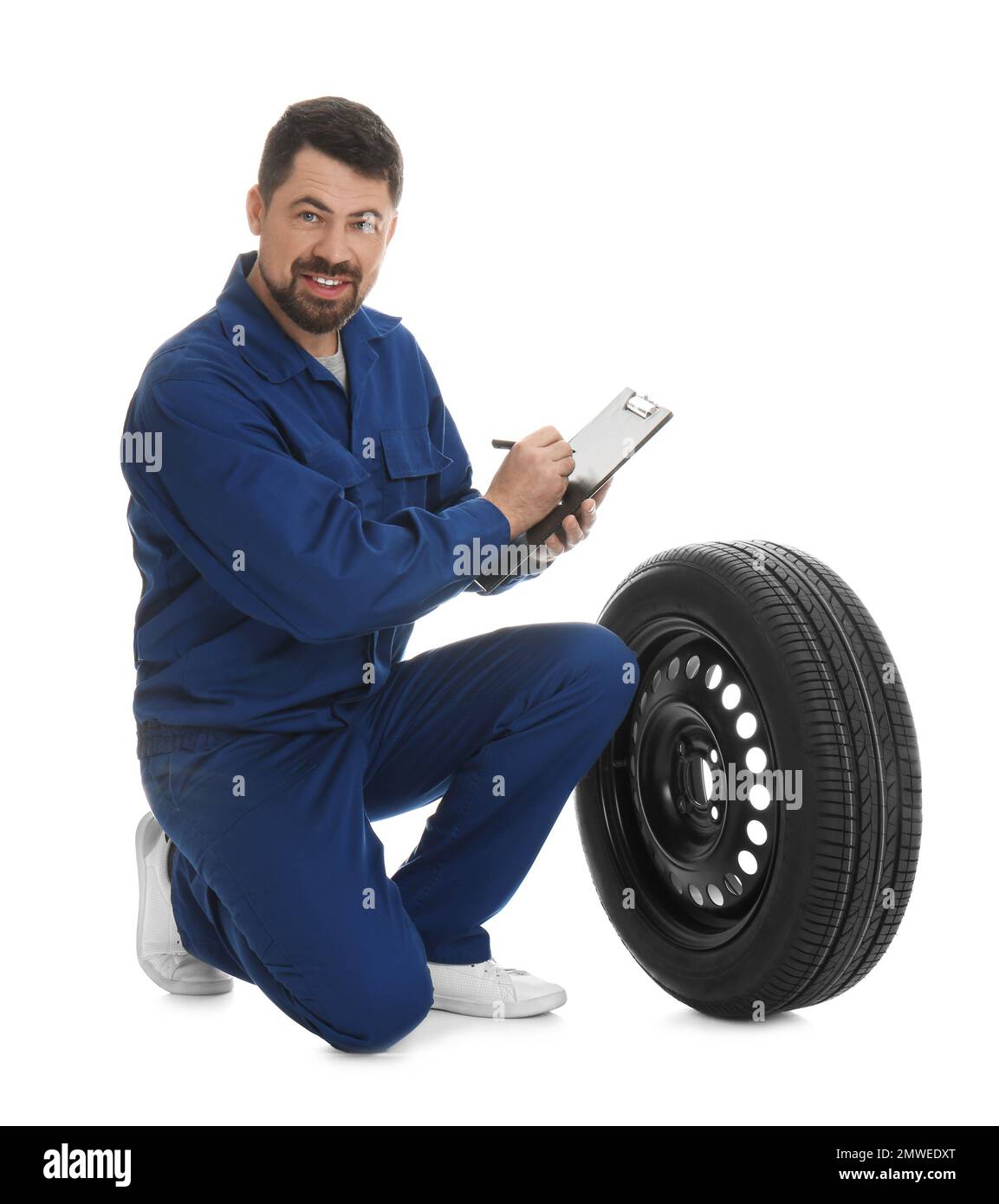 Professional auto mechanic with wheel and clipboard on white background ...