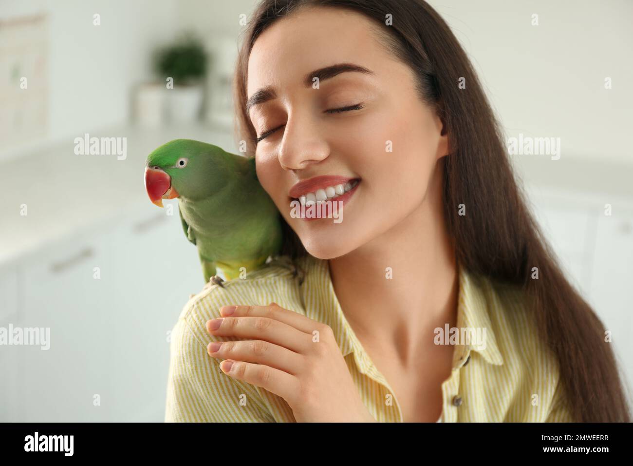Young woman with Alexandrine parakeet indoors. Cute pet Stock Photo - Alamy