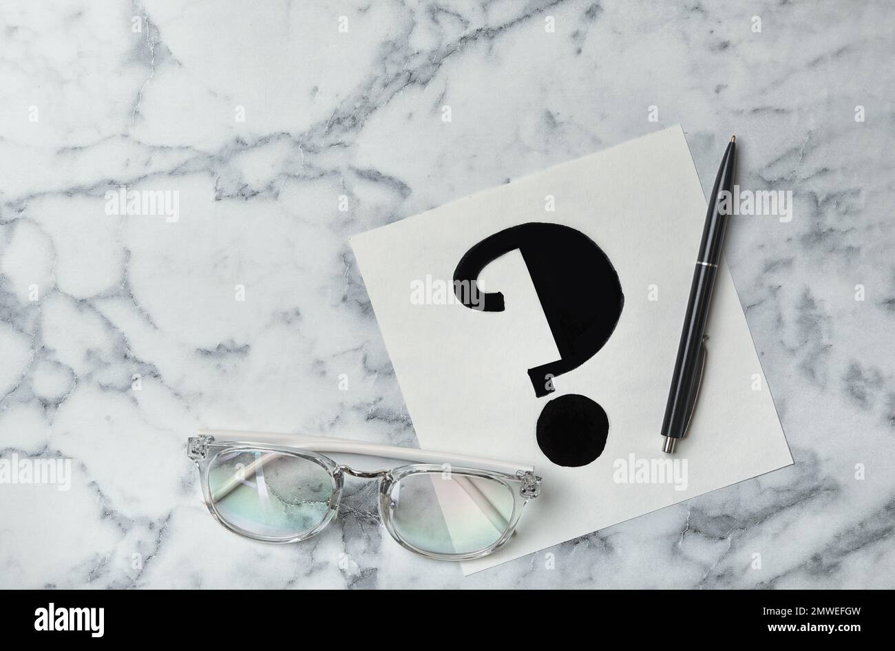 Note with question mark, eyeglasses and pen on white marble table, flat ...