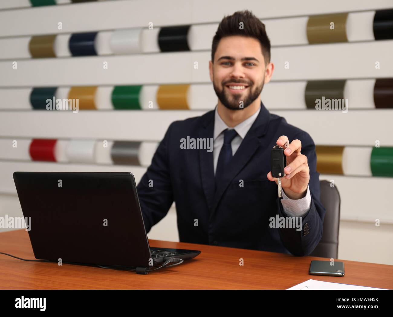 Salesman with car key at desk in office Stock Photo - Alamy