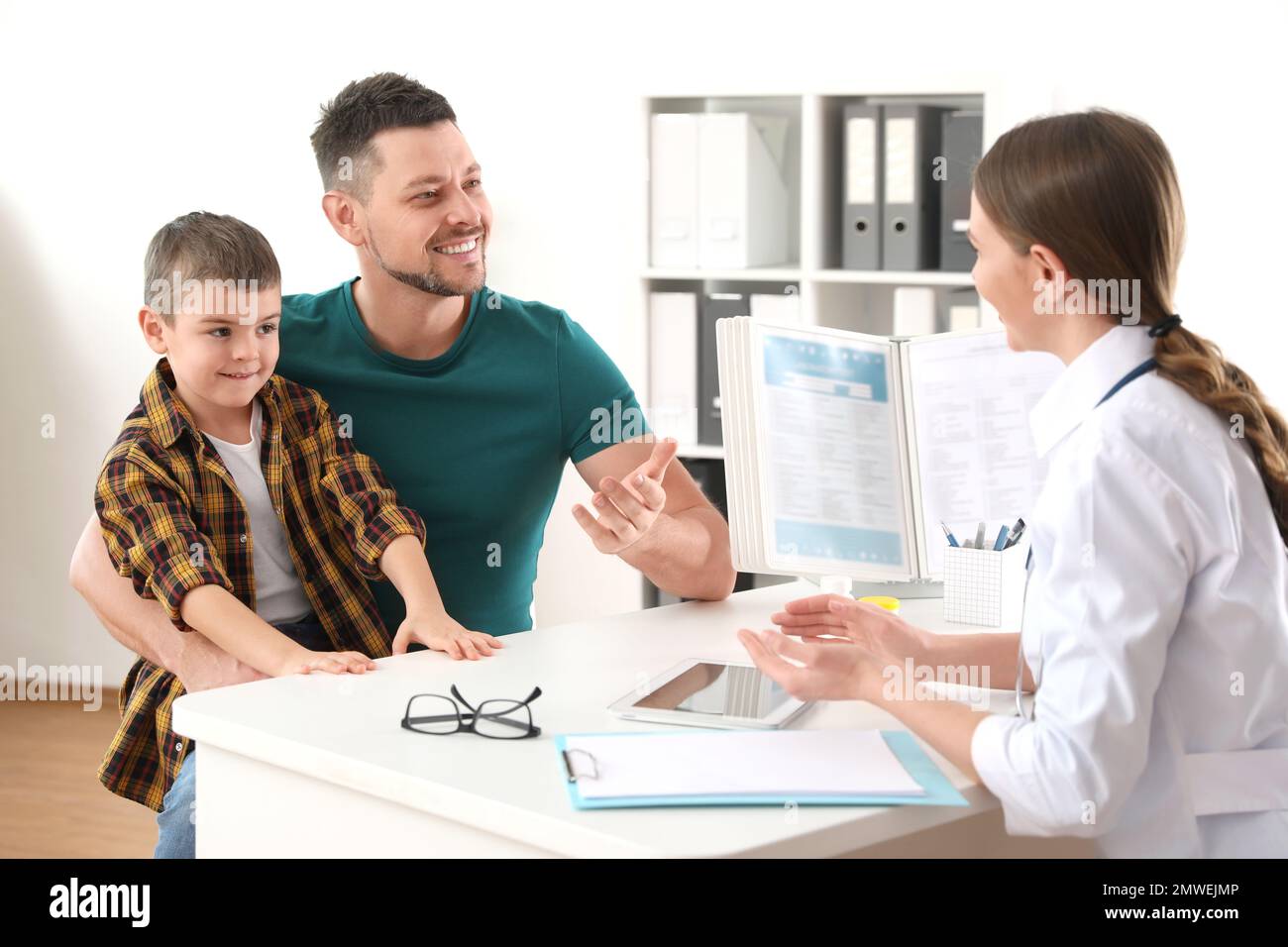 Father and son visiting pediatrician. Doctor working with little ...