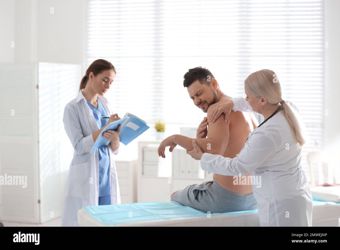 Female orthopedist examining patient's arm in clinic Stock Photo - Alamy