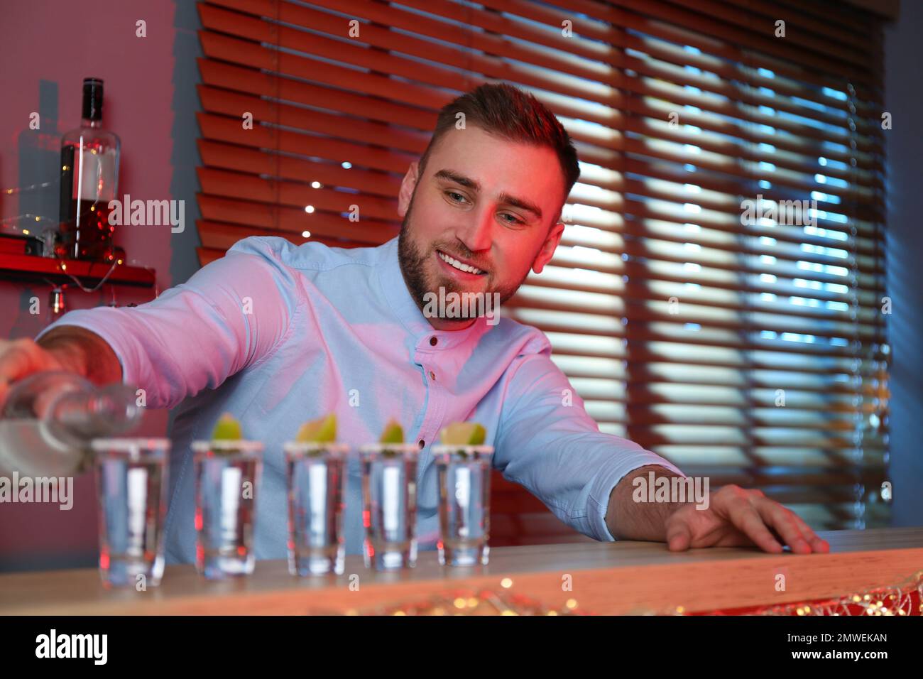 Bartender pouring Mexican Tequila into shot glasses at bar counter ...