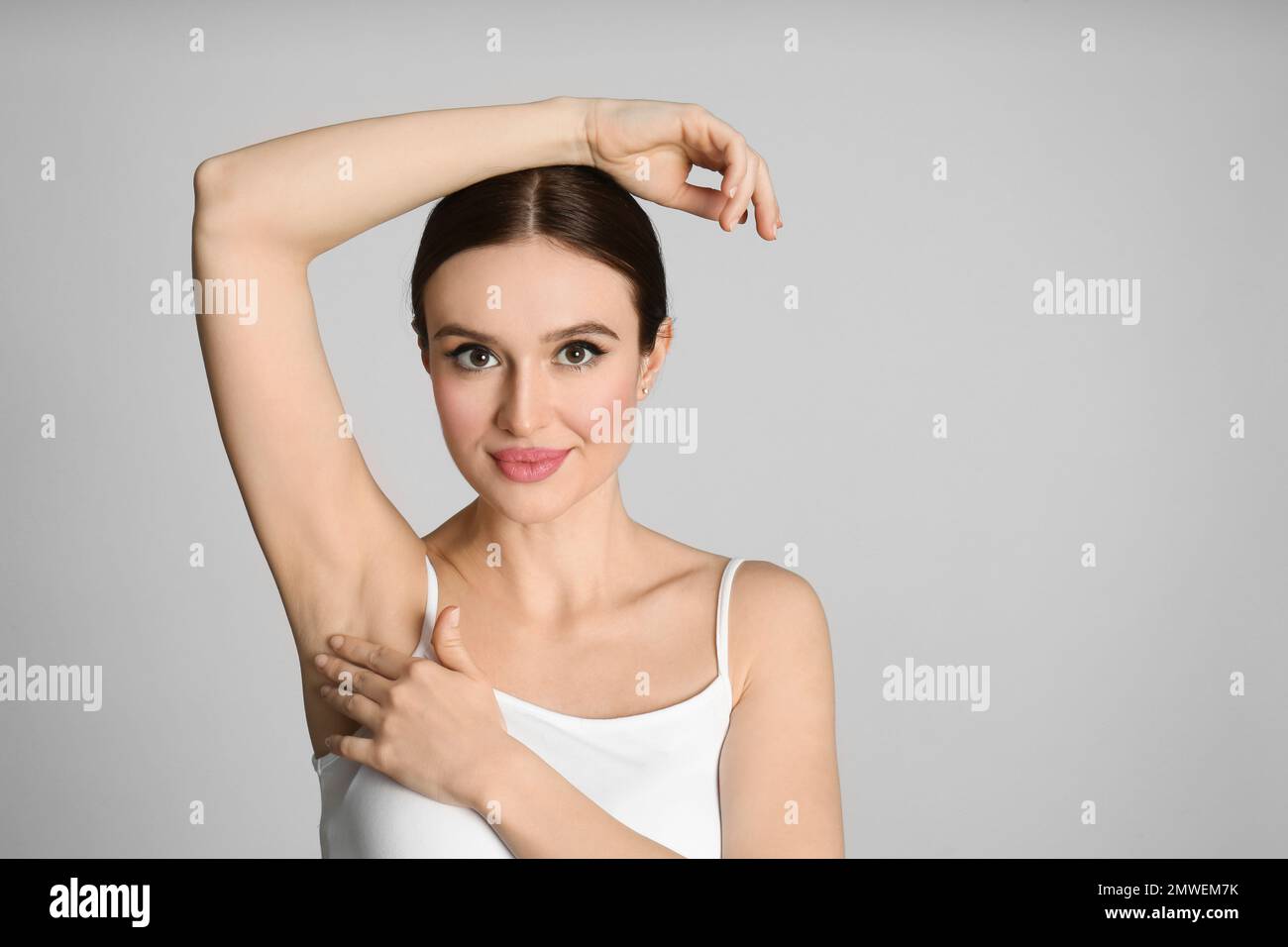 Young beautiful woman showing armpit with smooth clean skin on light ...