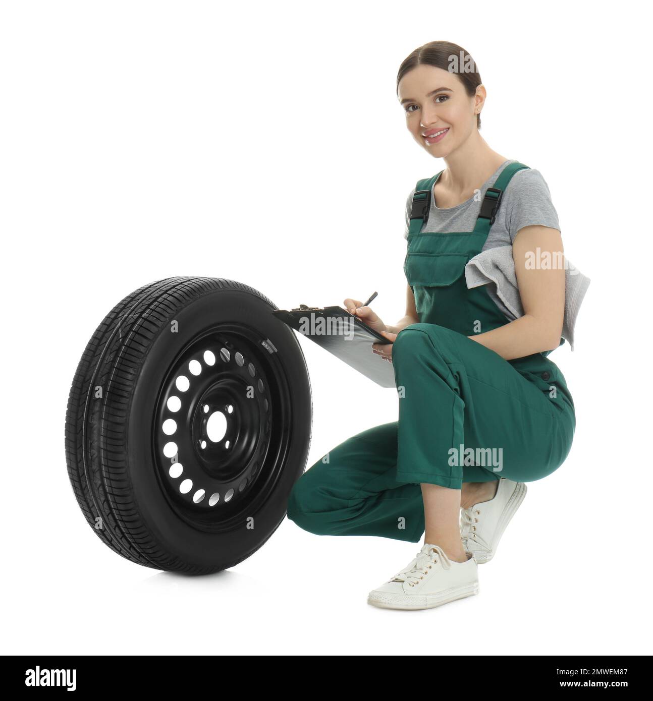 Professional auto mechanic with wheel and clipboard on white background ...
