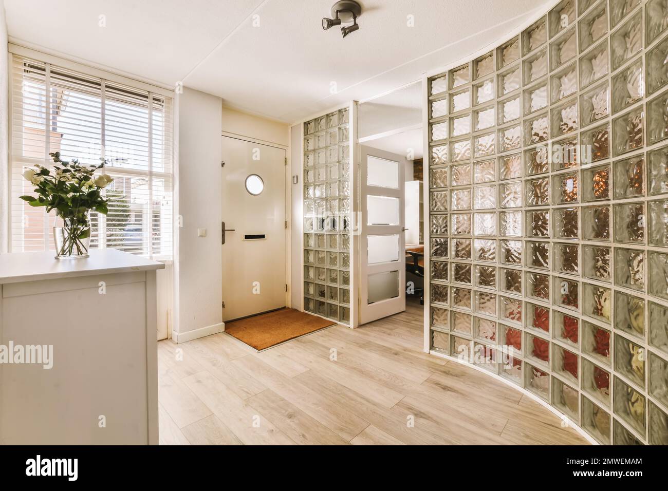 a glass block wall in a hallway with wooden flooring and white trim on ...