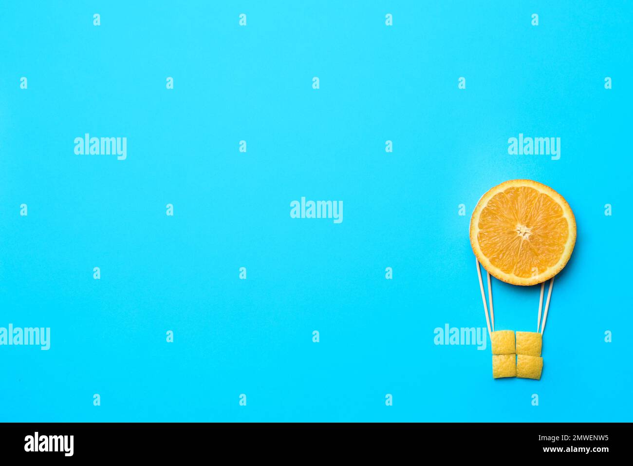 Hot air balloon made of orange on blue background, flat lay. Space for ...