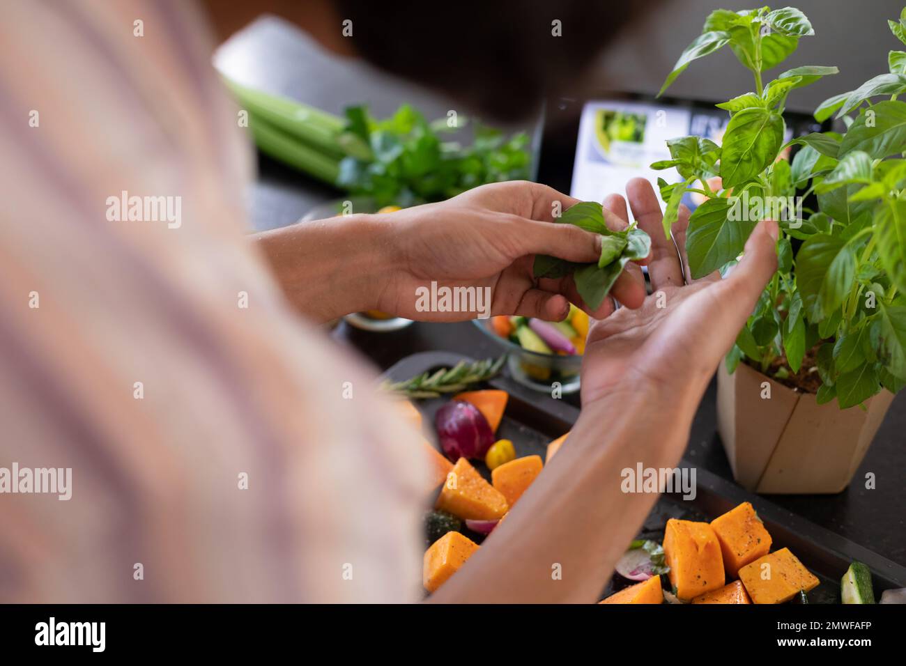 Midsection of biracial man cooking, seasoning vegetables in kitchen ...