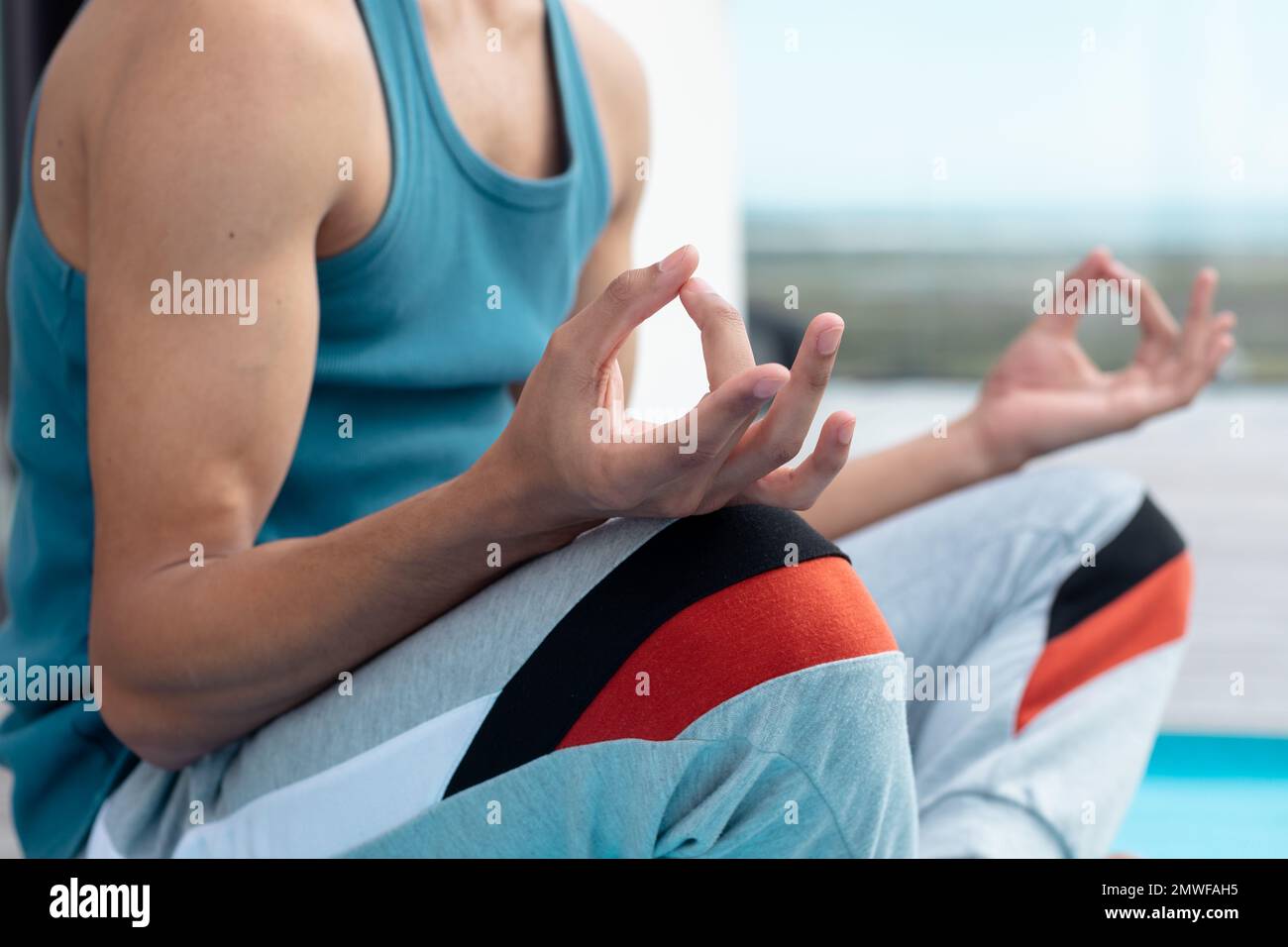 Midsection of biracial man doing yoga, meditating on balcony Stock ...