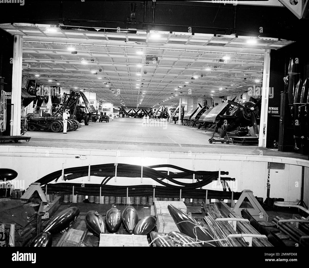 Wings folded, Navy planes are stored on the hangar deck of the carrier ...