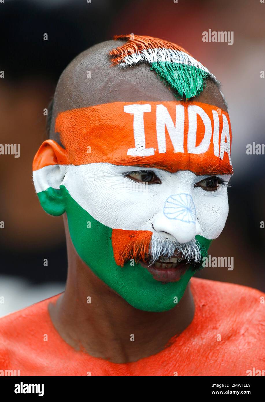 An Indian cricket fan with his face painted in the colors of the ...