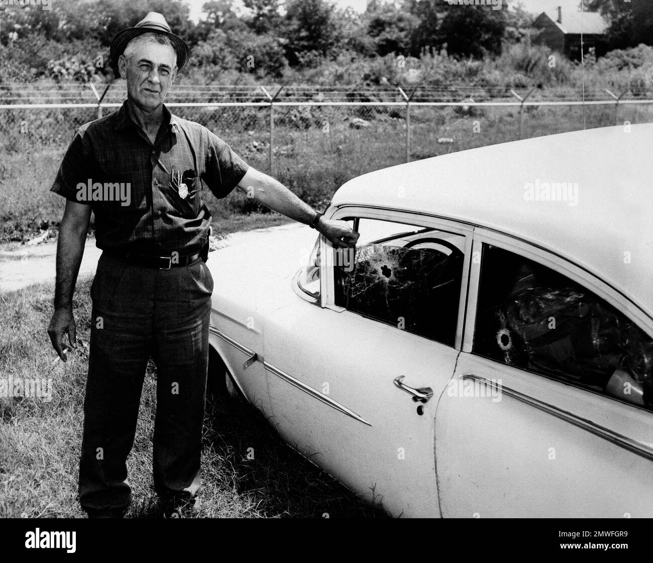 Deputy Sheriff H.L. Pulleam points to bullet holes in the window of the ...