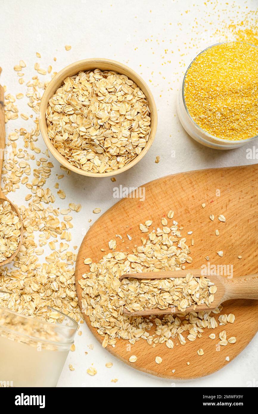 Bowls of oatmeal flakes and corn grits on light background Stock Photo ...