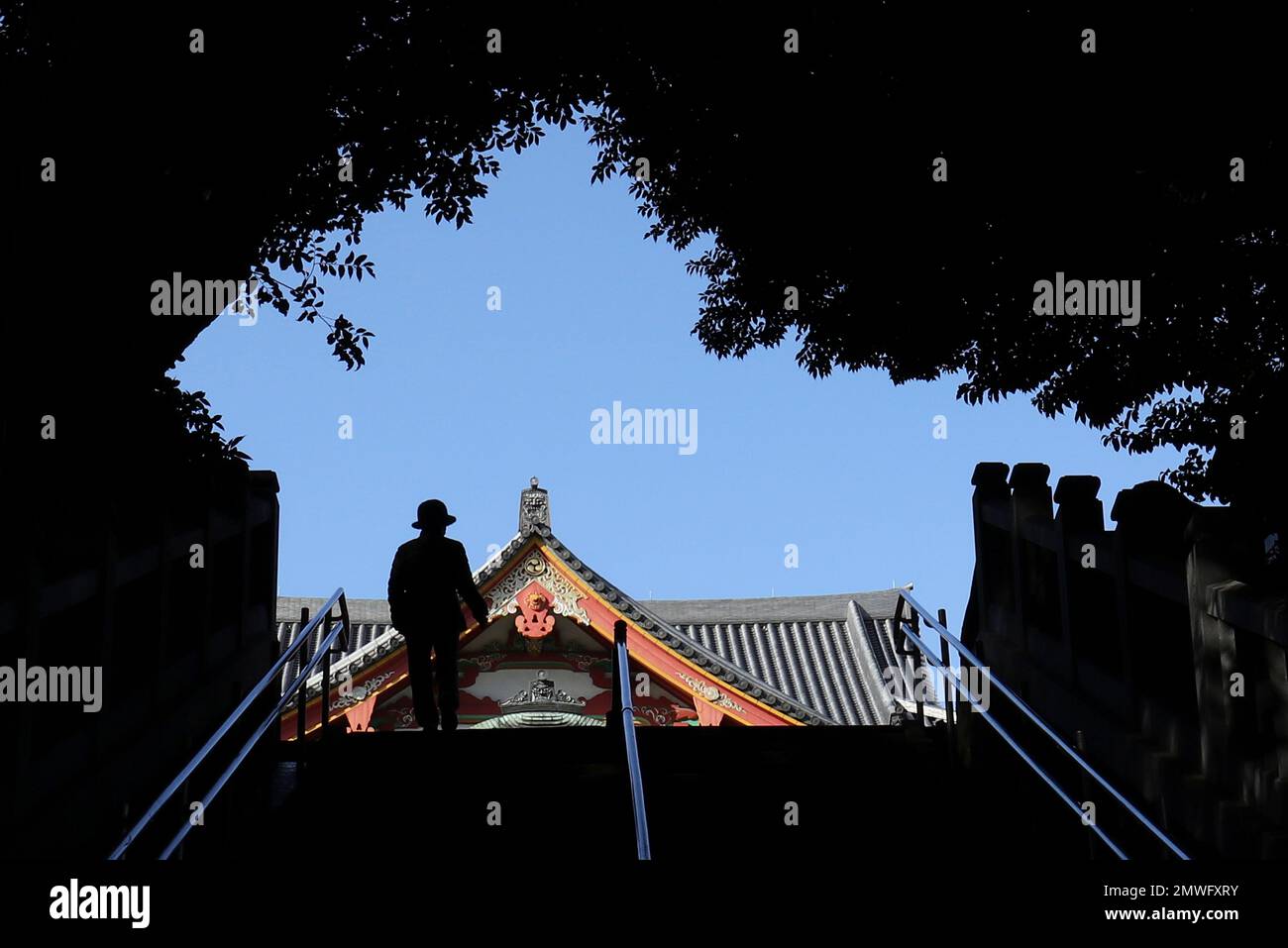 A woman walks up stone steps at Meguro fudo Ryusenji temple in Tokyo ...