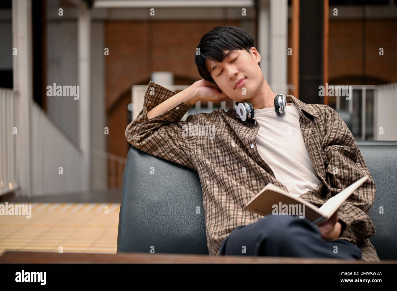 Relaxed and sleepy young Asian man in trendy outfit eyes closed ...