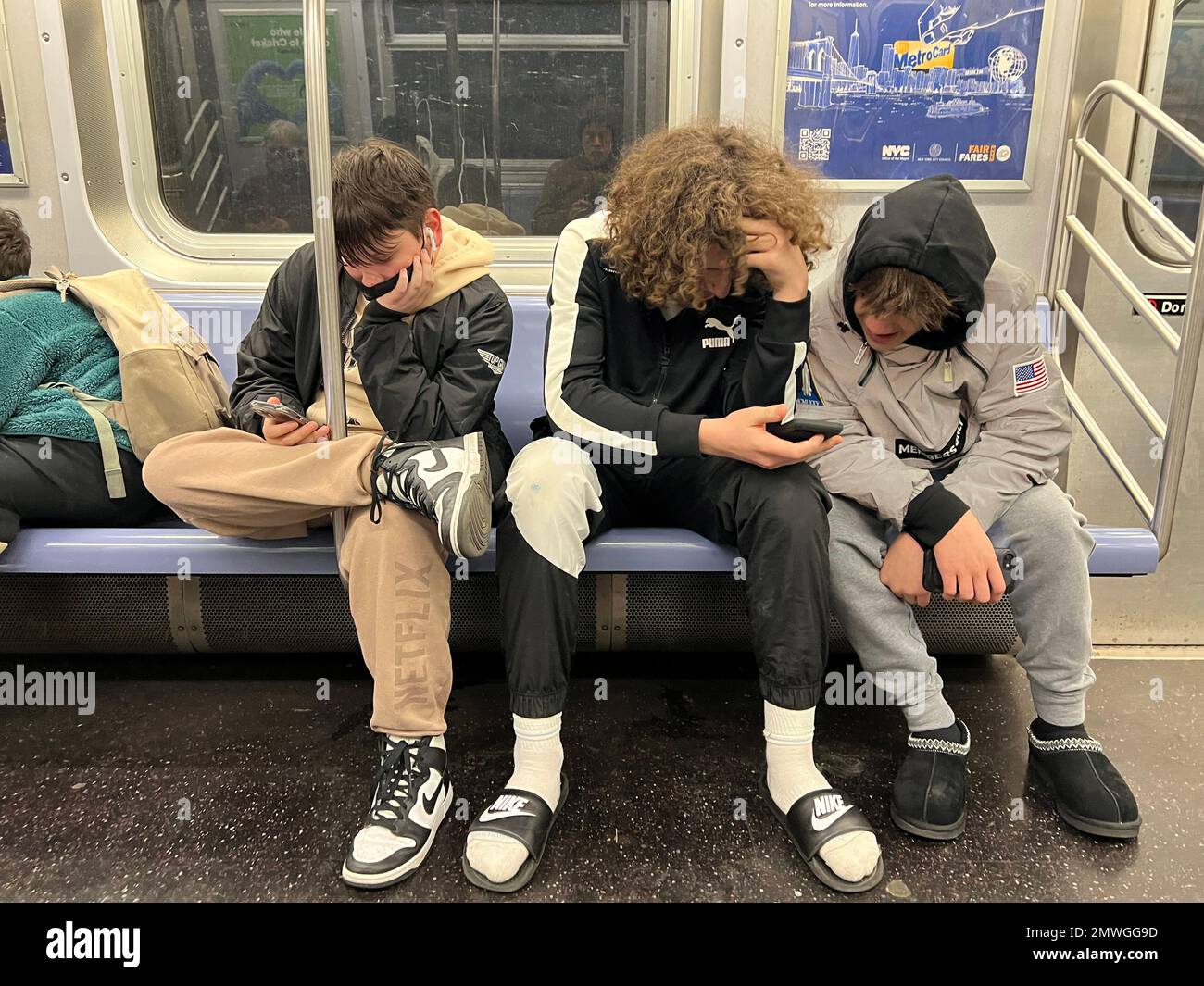 Three teenage boys doing screen time while they ride a subway train in ...