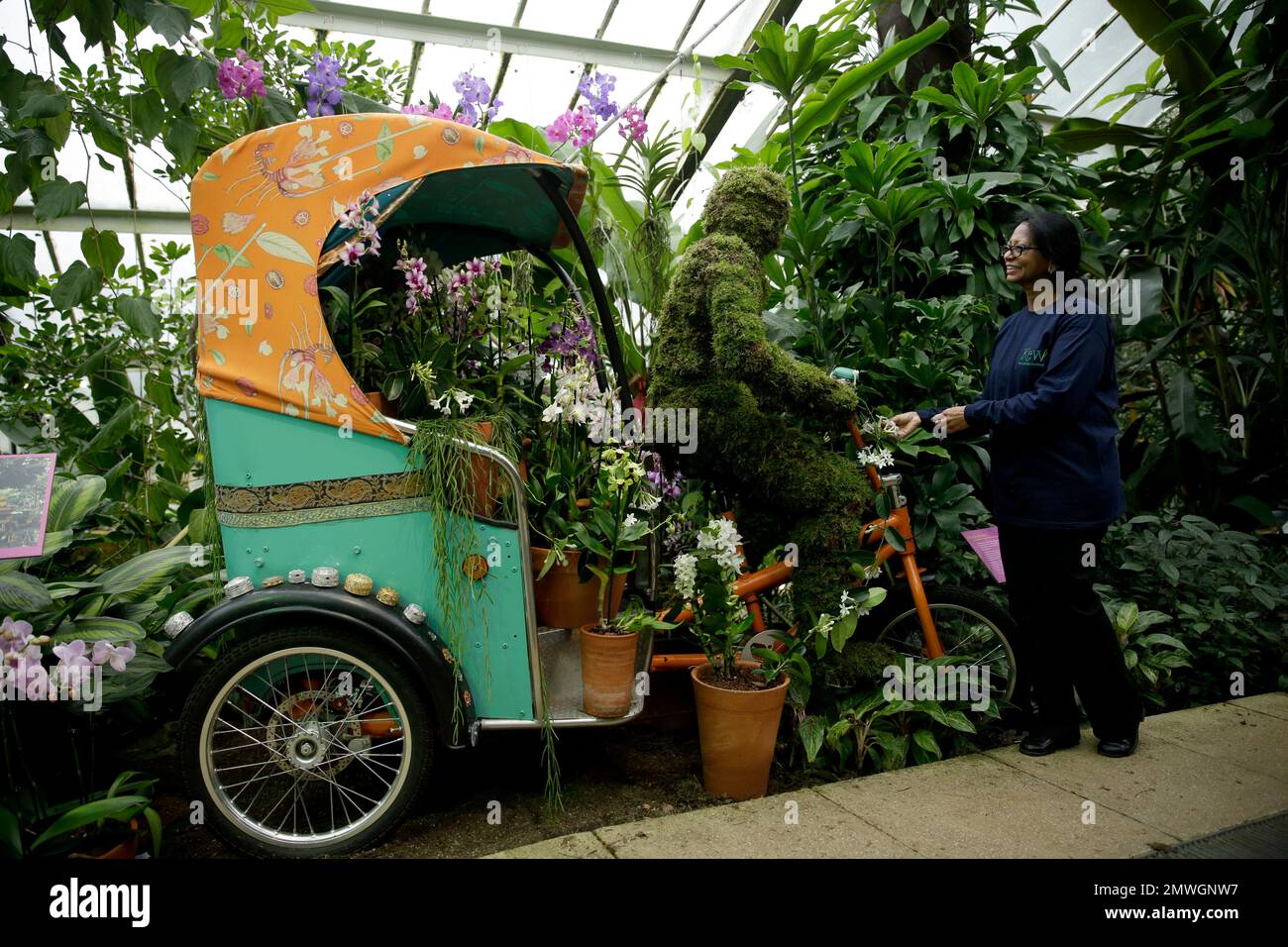 A staff member poses for photographs with a rickshaw display during a ...