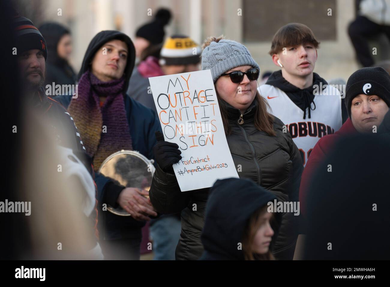 An educator holds a sign expressing her opinion during a rally in ...