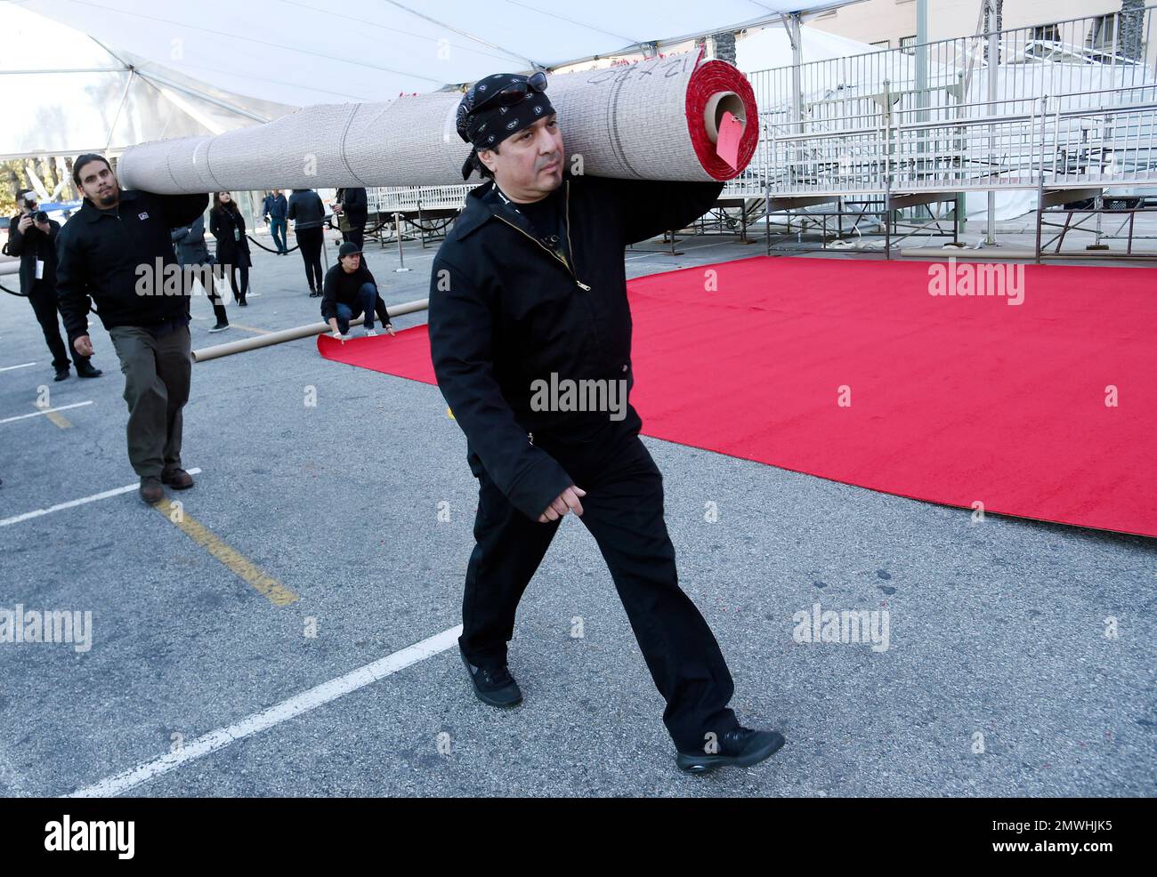 Crew members David Salas, left, and Marc D'Larosa carry a roll of red ...