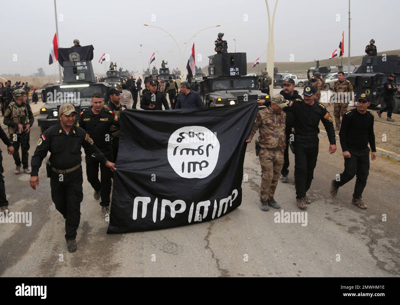 Iraq's special forces troops hold a flag of the Islamic State group ...