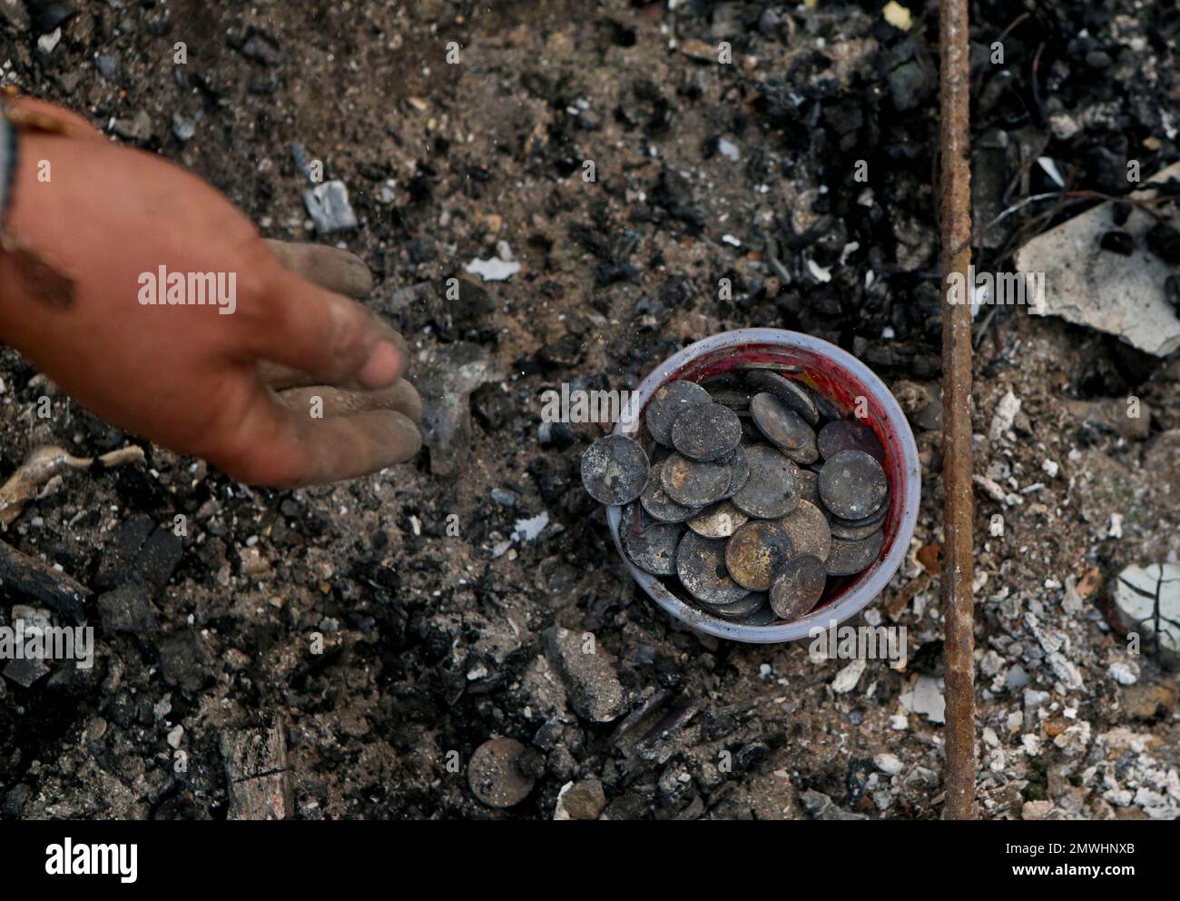 Claudia Salinas picks up charred coins, which belong to her daughter ...